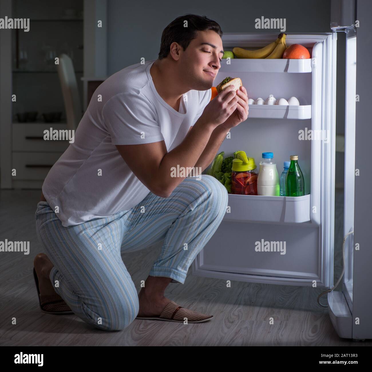 The man at the fridge eating at night Stock Photo - Alamy
