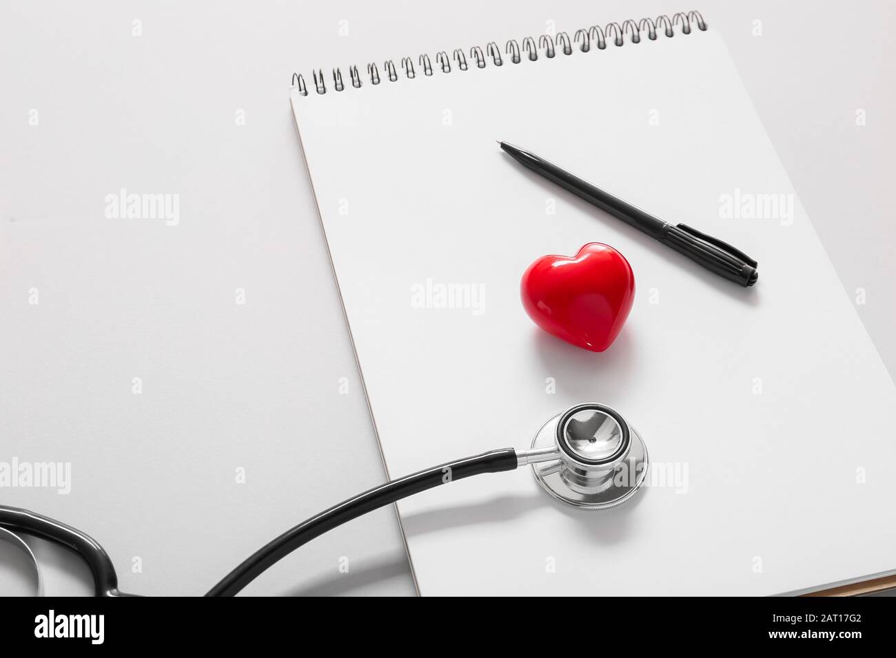 Stethoscope, red heart and notebook on light background. Cardiology ...