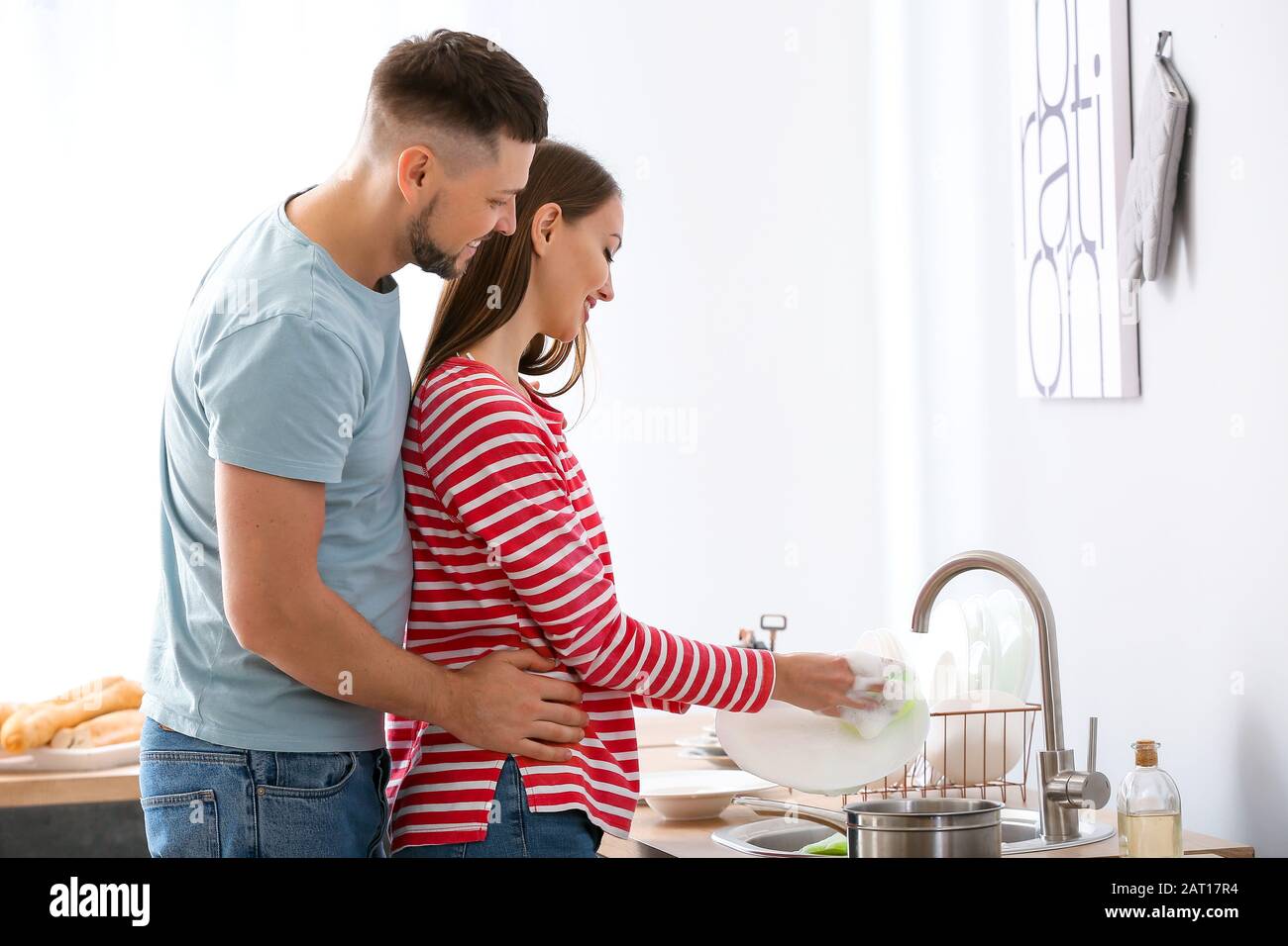 Happy couple washing dishes in kitchen Stock Photo - Alamy