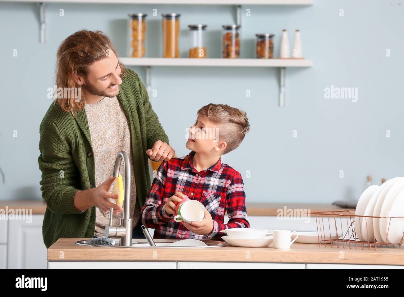 Father and son washing dishes in kitchen Stock Photo - Alamy