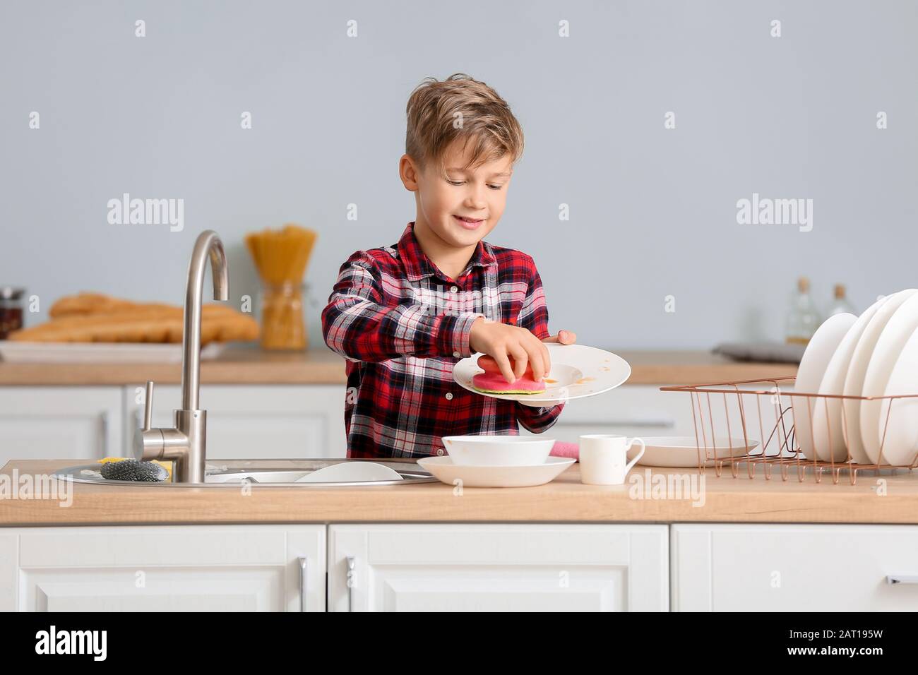 Little boy washing dishes in kitchen Stock Photo - Alamy