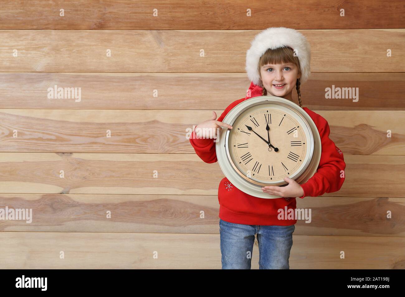 Little girl with clock on wooden background. Christmas countdown ...