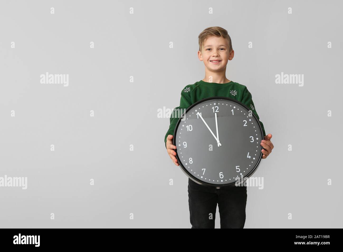 Little boy with clock on light background. Christmas countdown concept ...