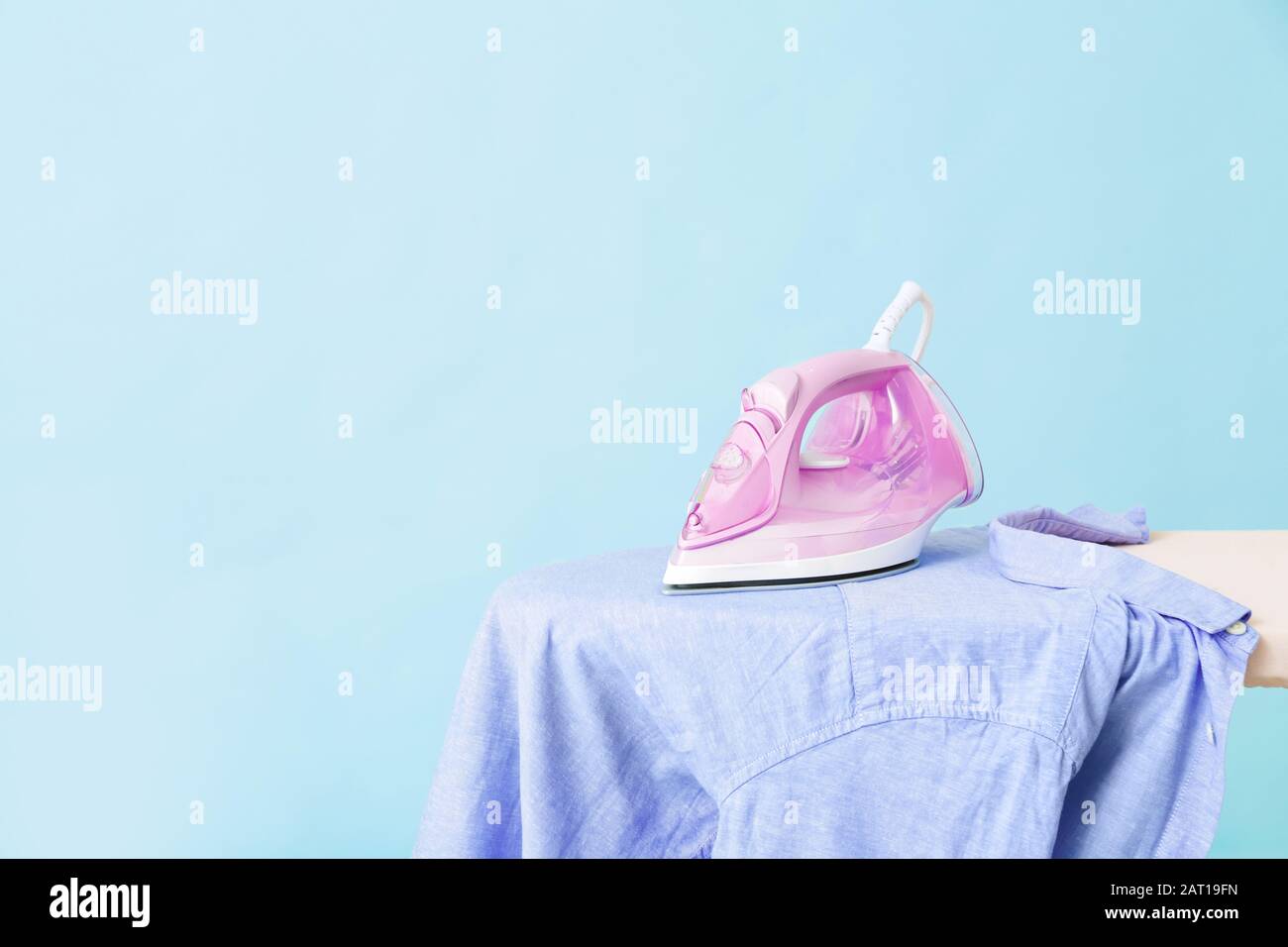 Iron and clean clothes on board against color background Stock Photo ...