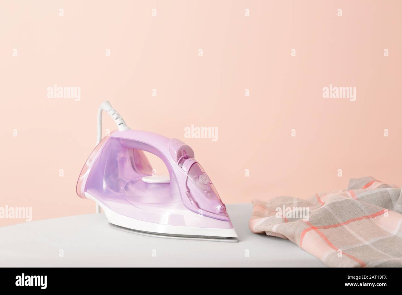 Iron and clean clothes on board against color background Stock Photo ...