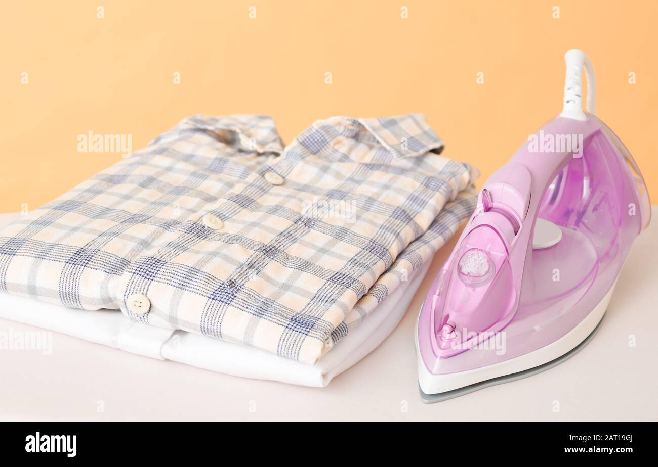 Iron and clean clothes on board against color background Stock Photo ...