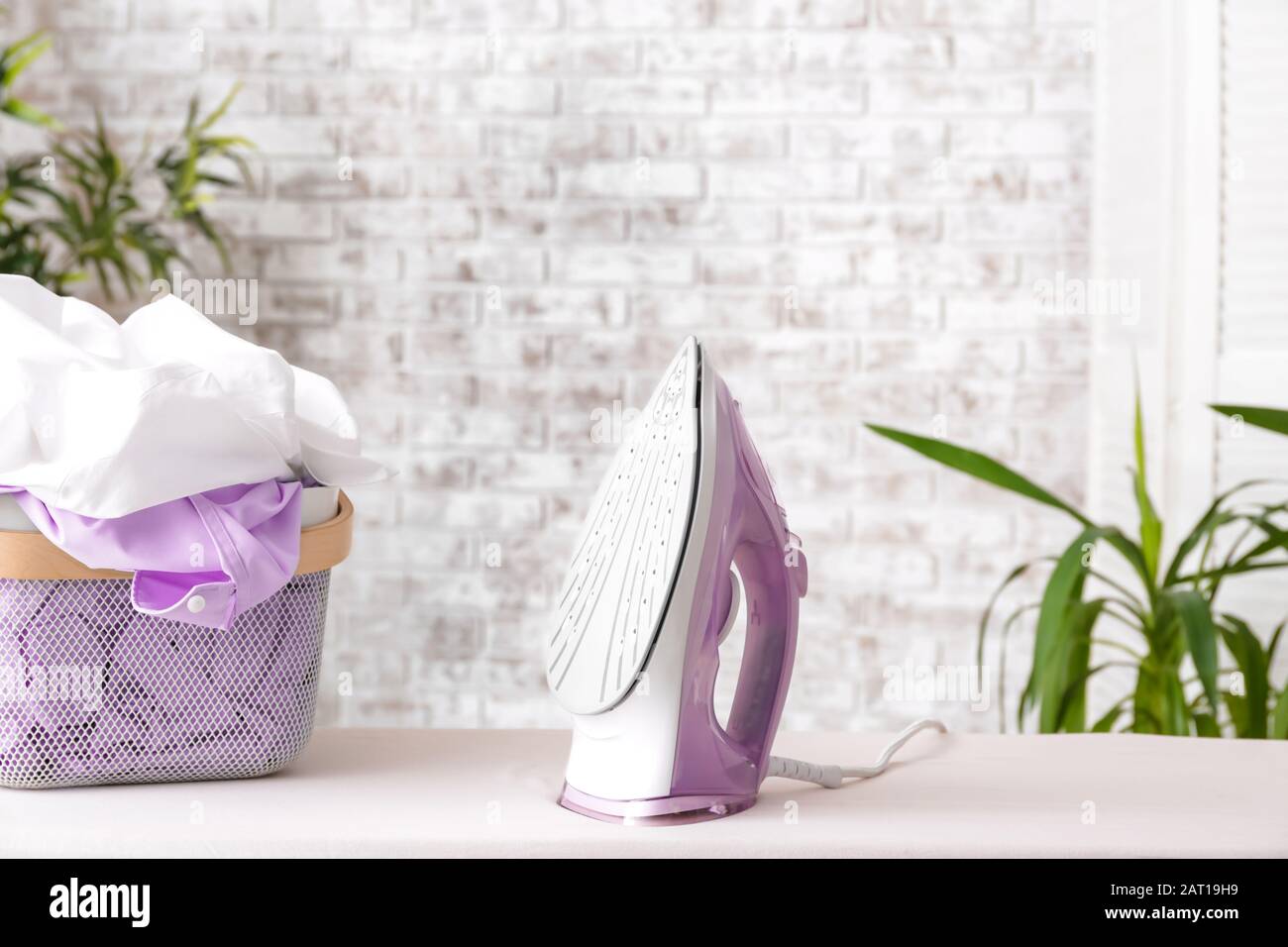 Iron and clean clothes in basket on board in room Stock Photo - Alamy