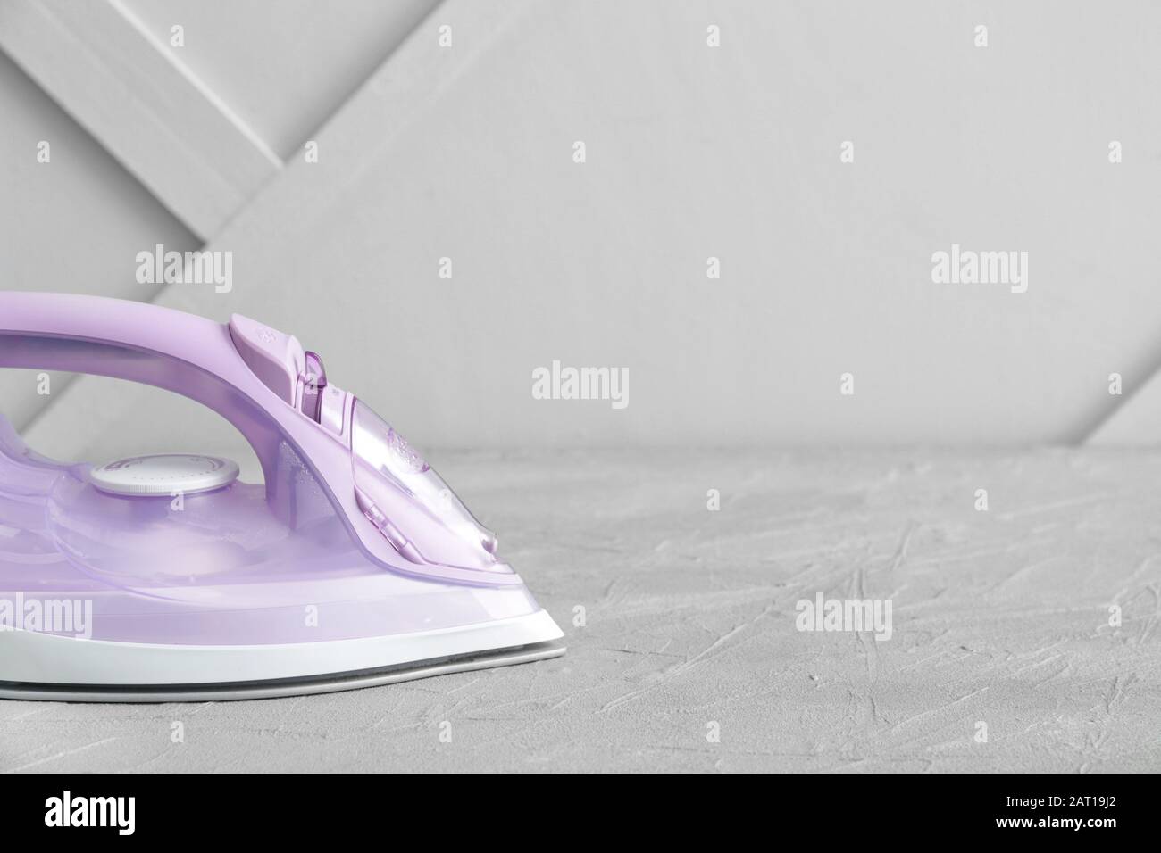 Electric iron on table against grey background Stock Photo - Alamy