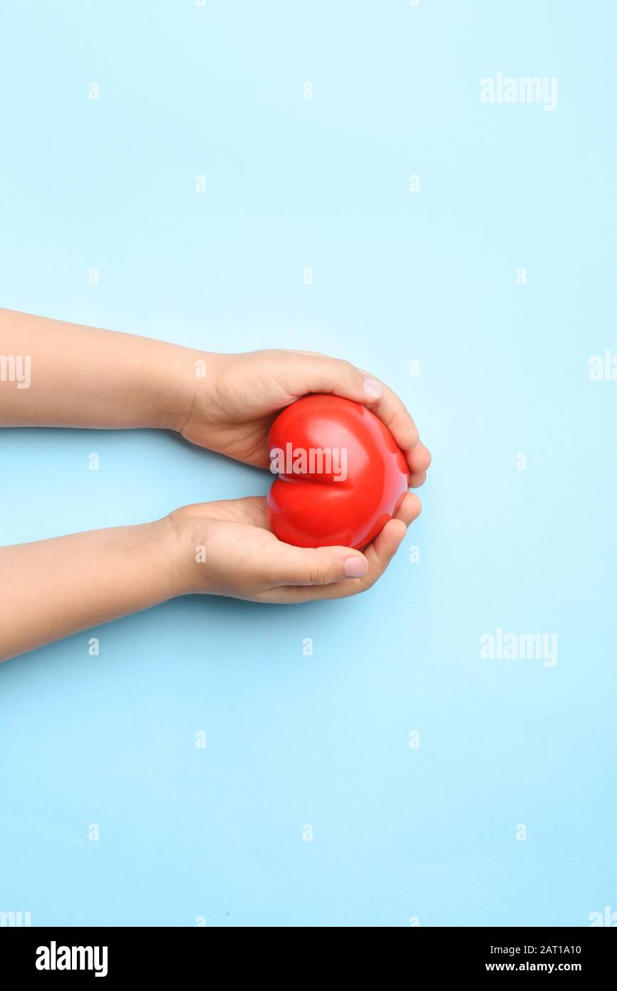 Child hands with red heart on color background. Cardiology concept ...