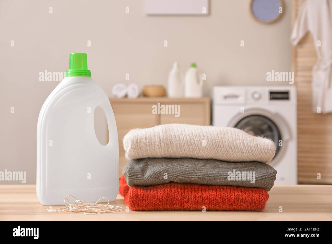 Clean laundry and washing liquid on table in bathroom Stock Photo - Alamy