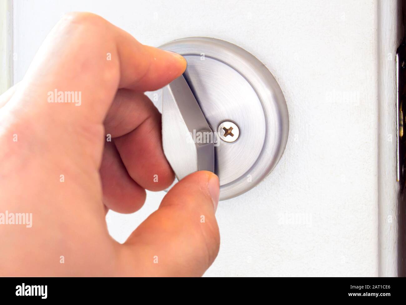 A person Shutting off a door with a round pocket door lock on a white ...