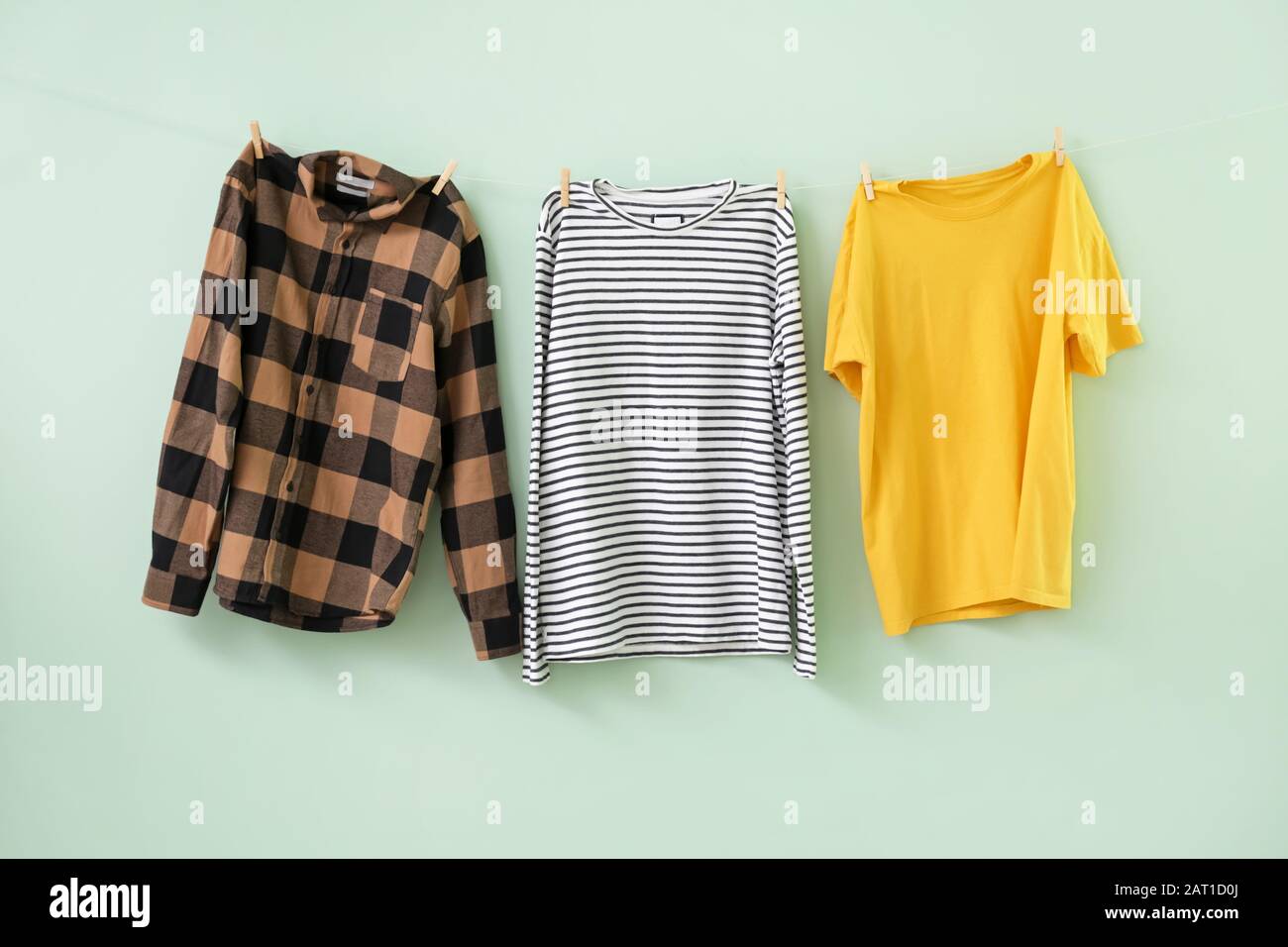 Clean clothes hanging on rope against color background Stock Photo - Alamy