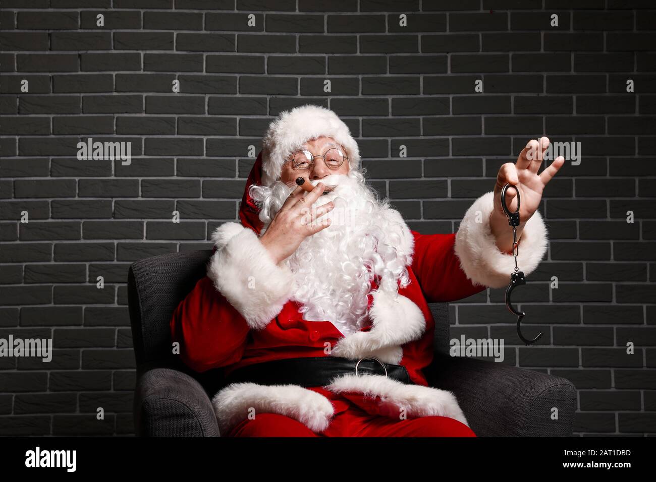 Funny drunk Santa Claus with handcuffs sitting in armchair against ...