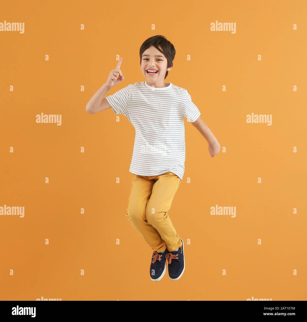 Jumping little boy with raised index finger on color background Stock ...