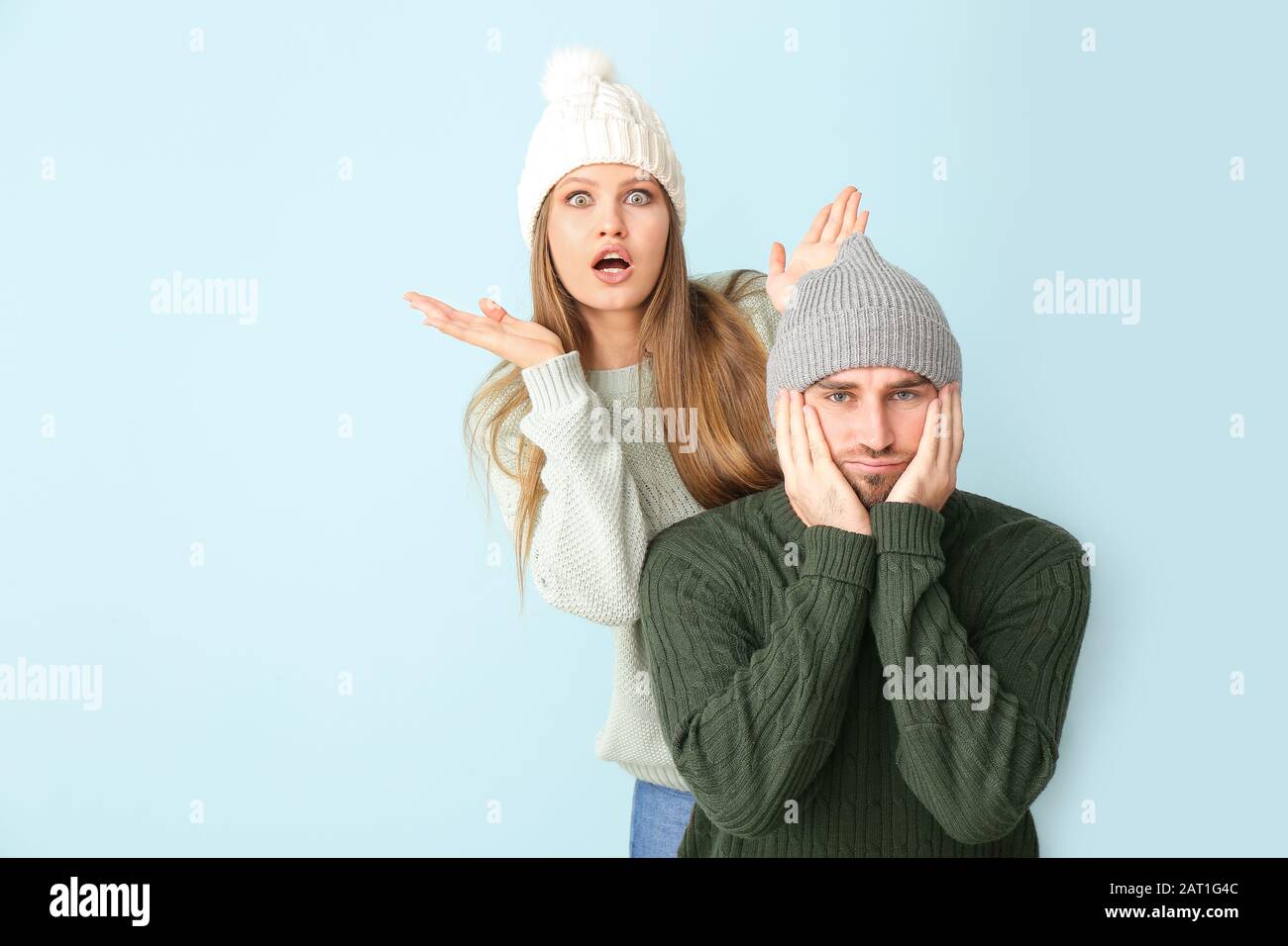 Portrait of emotional couple in winter clothes on color background ...