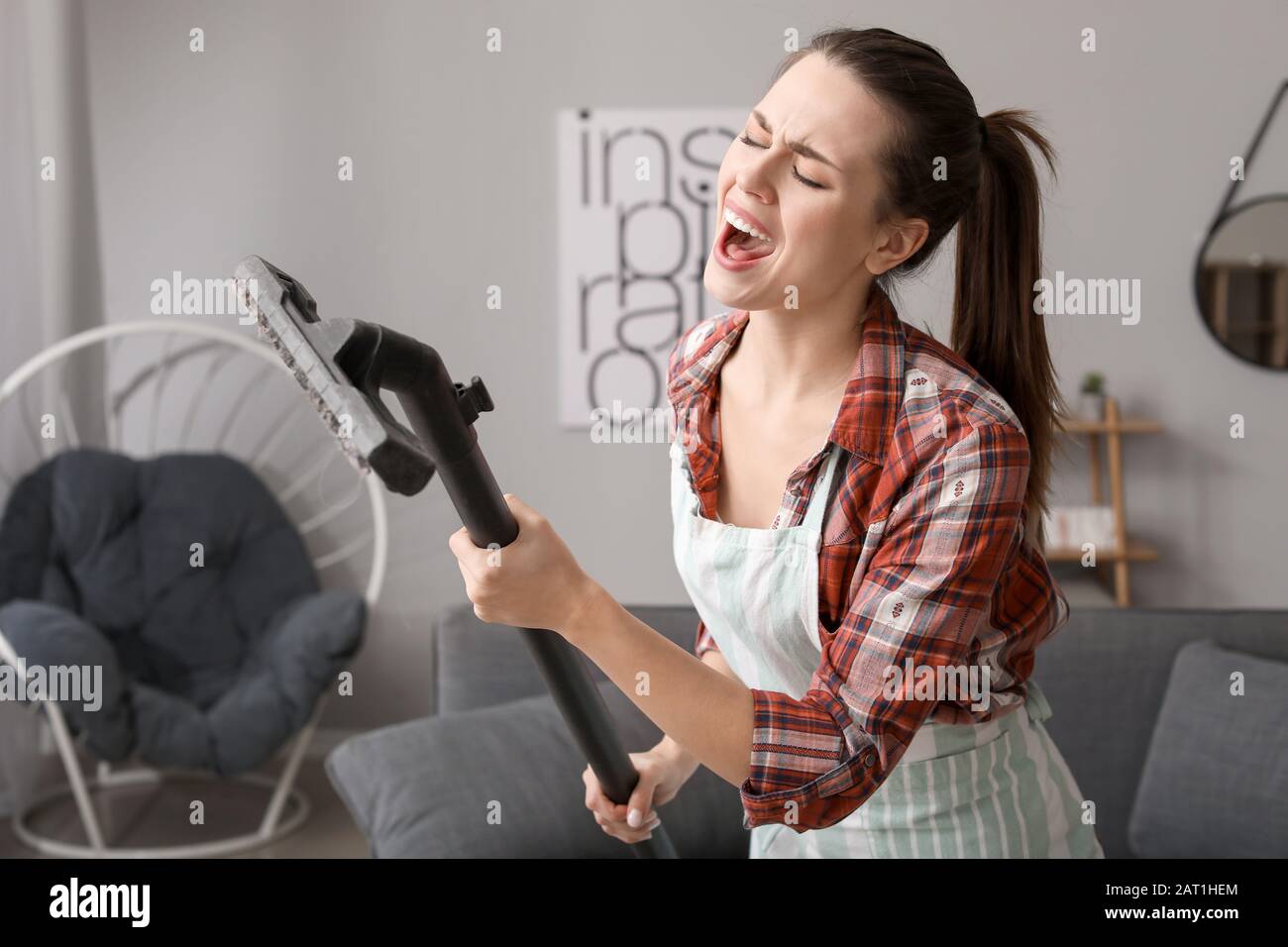 Young housewife singing while cleaning her flat Stock Photo - Alamy