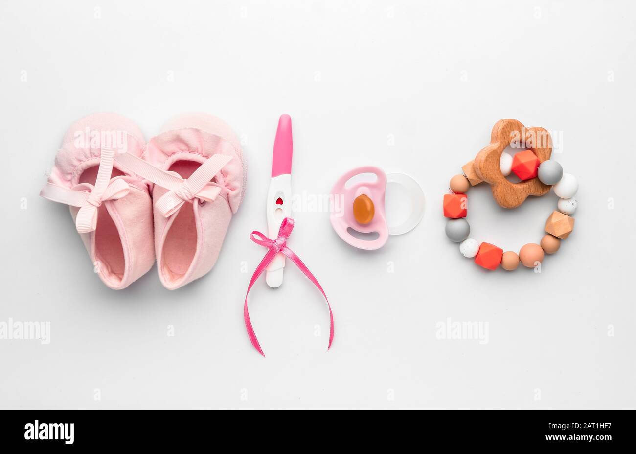 Pregnancy test, baby booties, pacifier and toy on white background ...