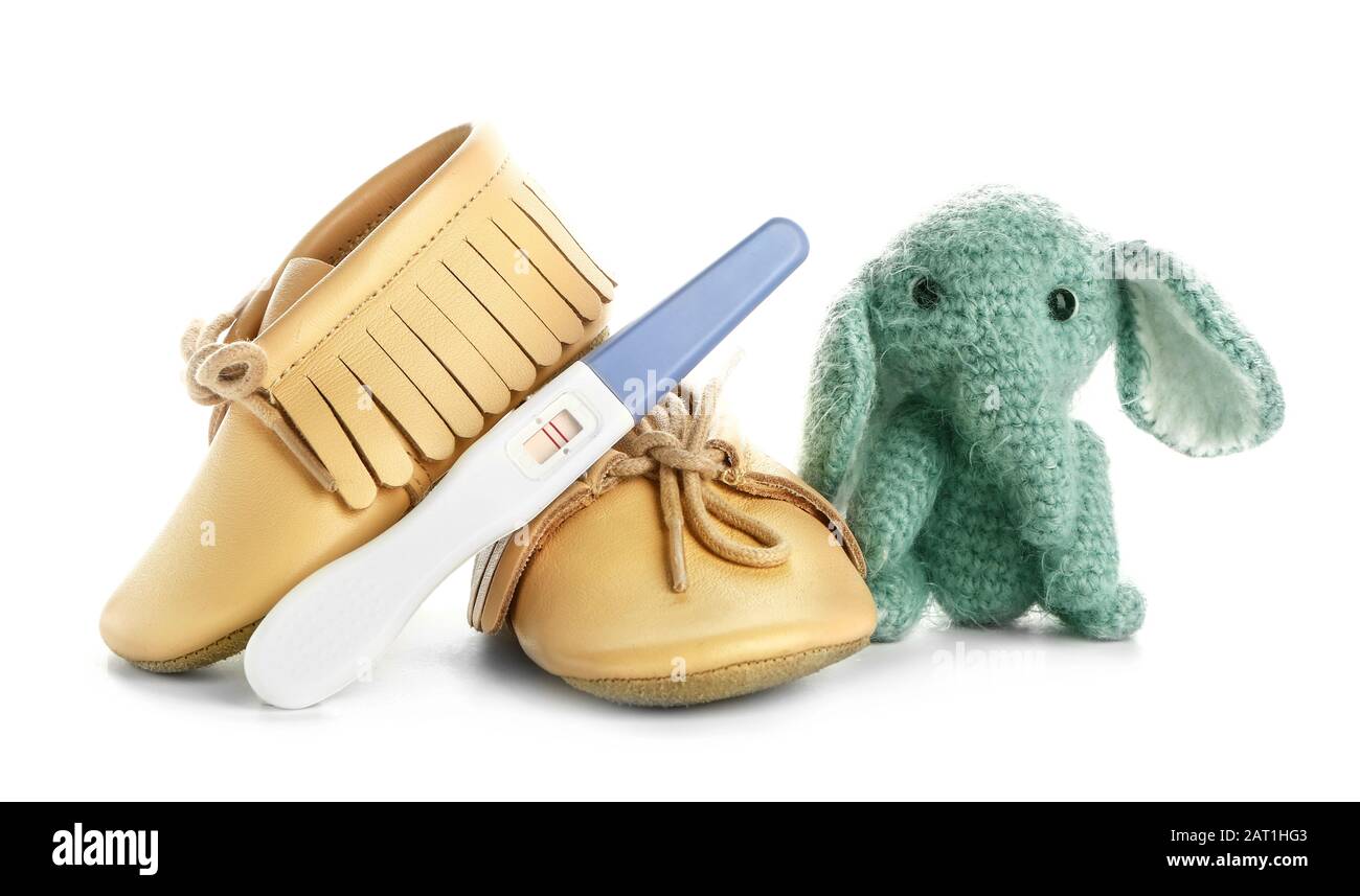 Pregnancy test, baby booties and toy on white background Stock Photo ...