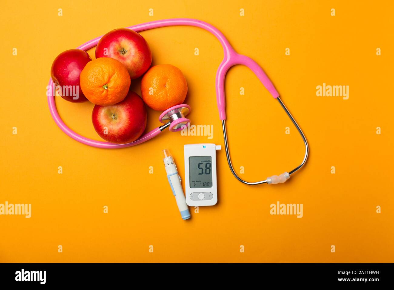 Digital glucometer, lancet pen, stethoscope and fruits on color ...