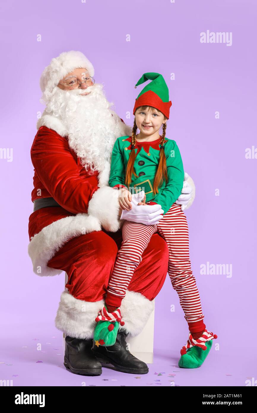 Santa Claus and little elf kid on color background Stock Photo - Alamy