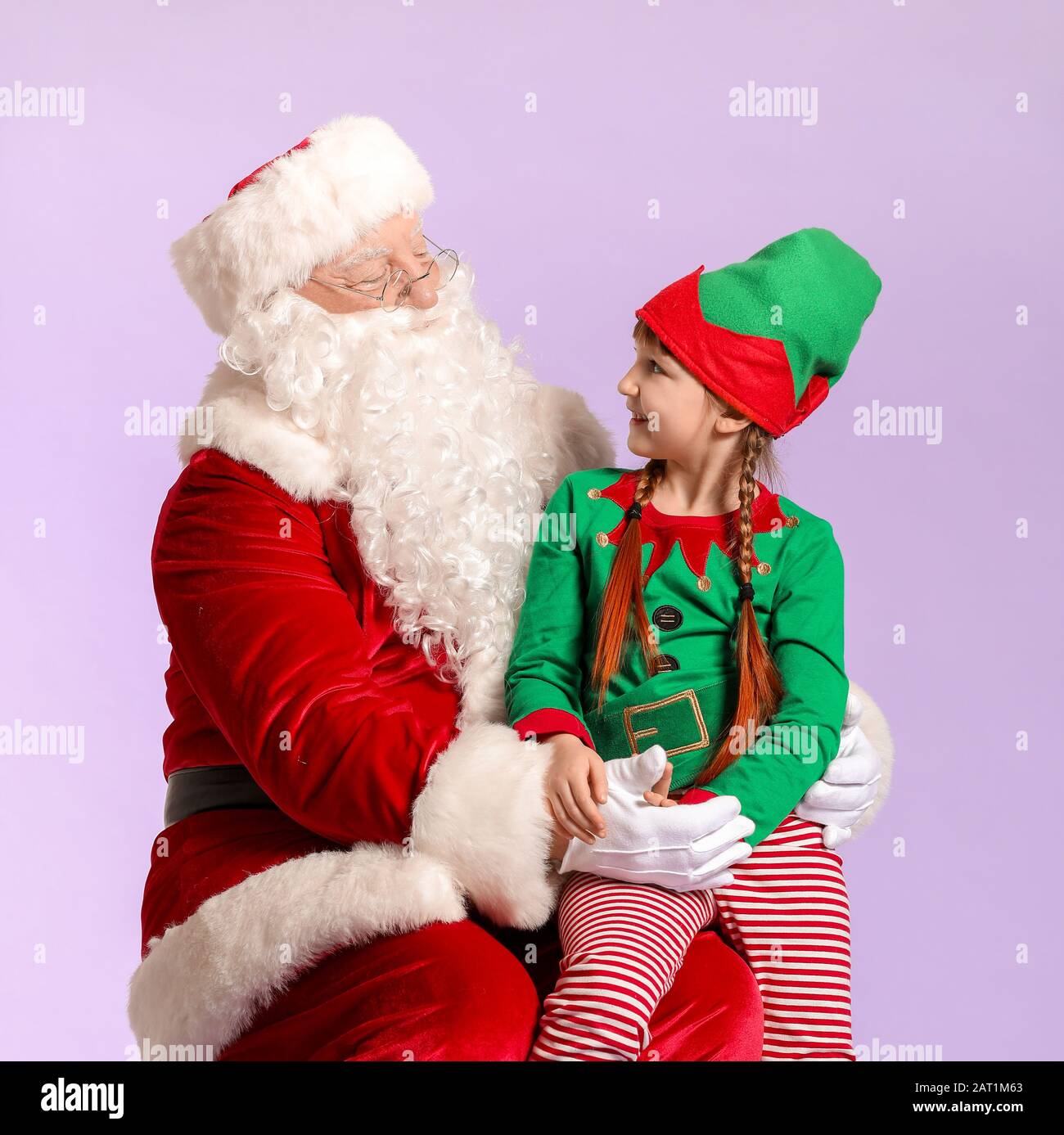 Santa Claus and little elf kid on color background Stock Photo - Alamy