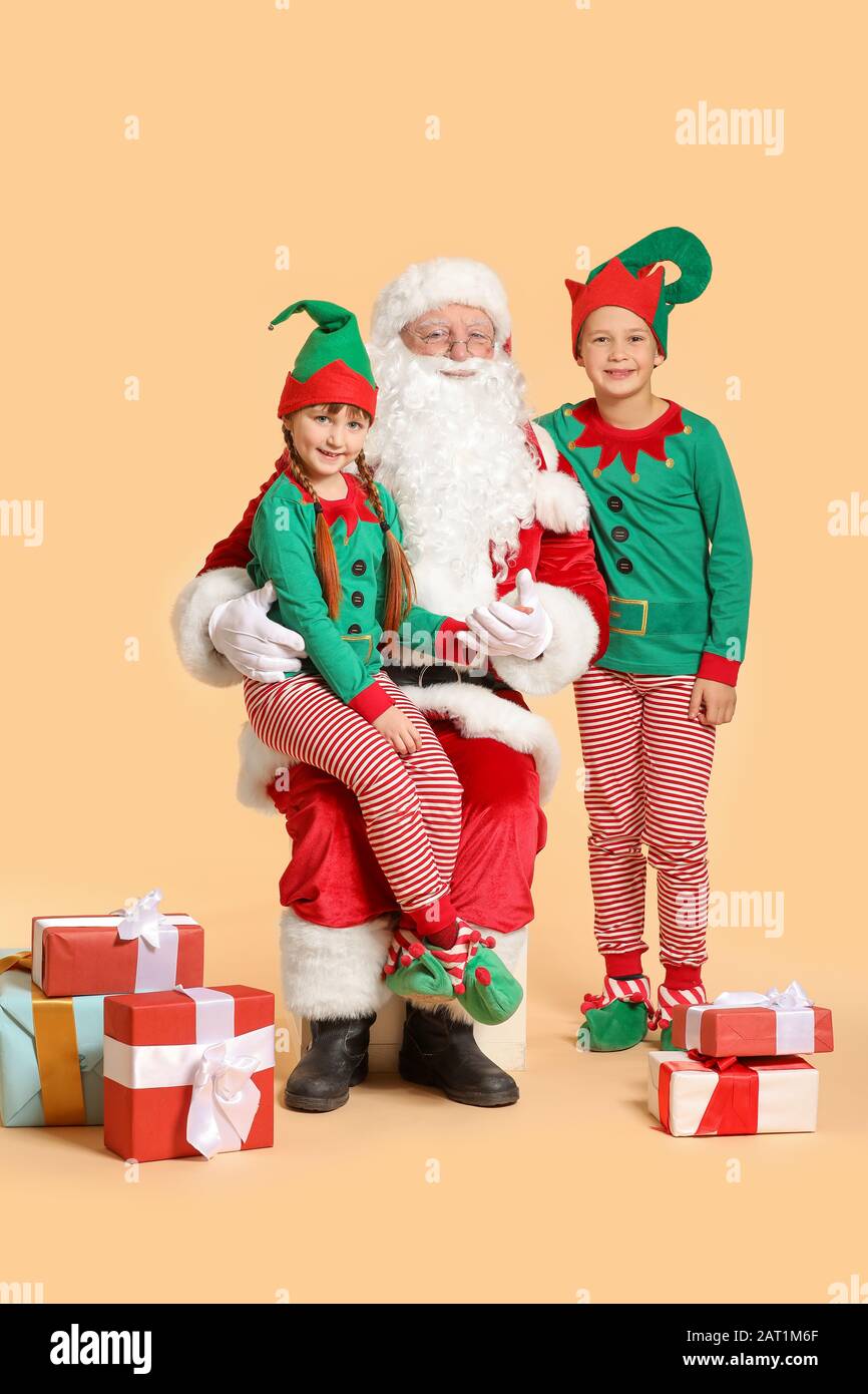 Santa Claus and little elf kids with gifts on color background Stock ...