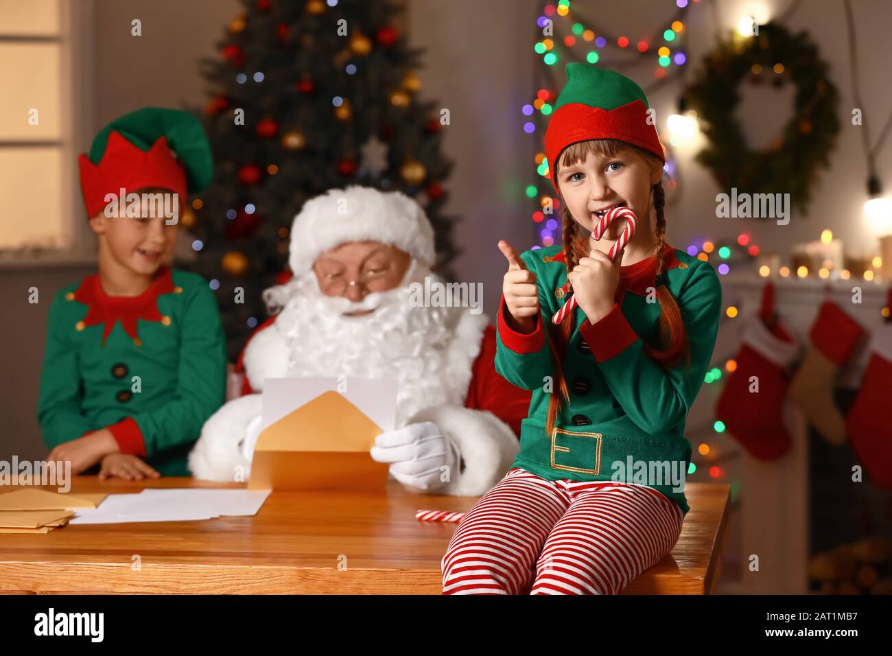 Elf kids with Santa Claus reading letter at home Stock Photo - Alamy