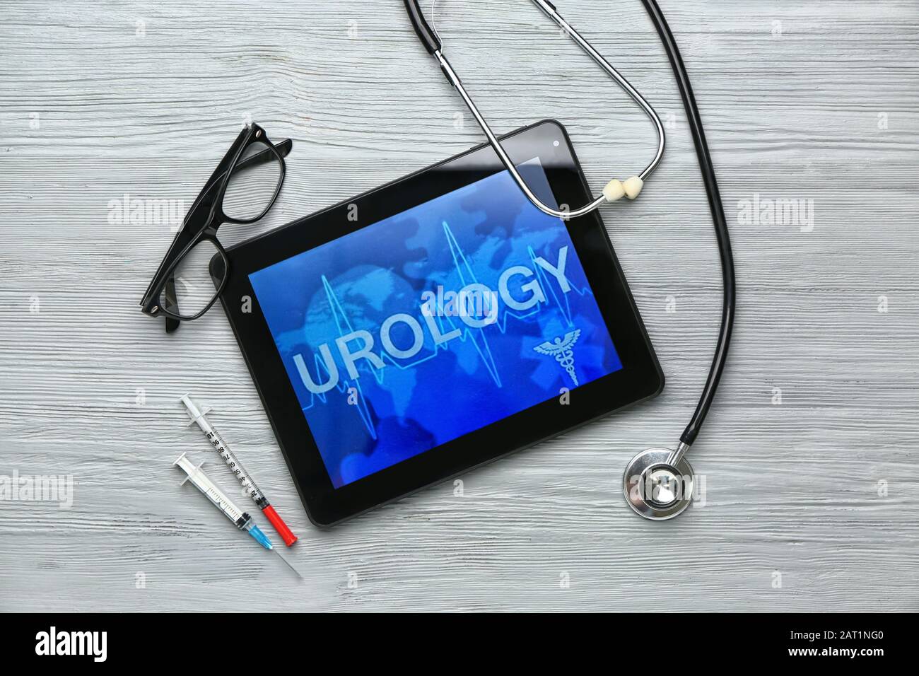Tablet computer with word UROLOGY on screen, stethoscope and syringes ...