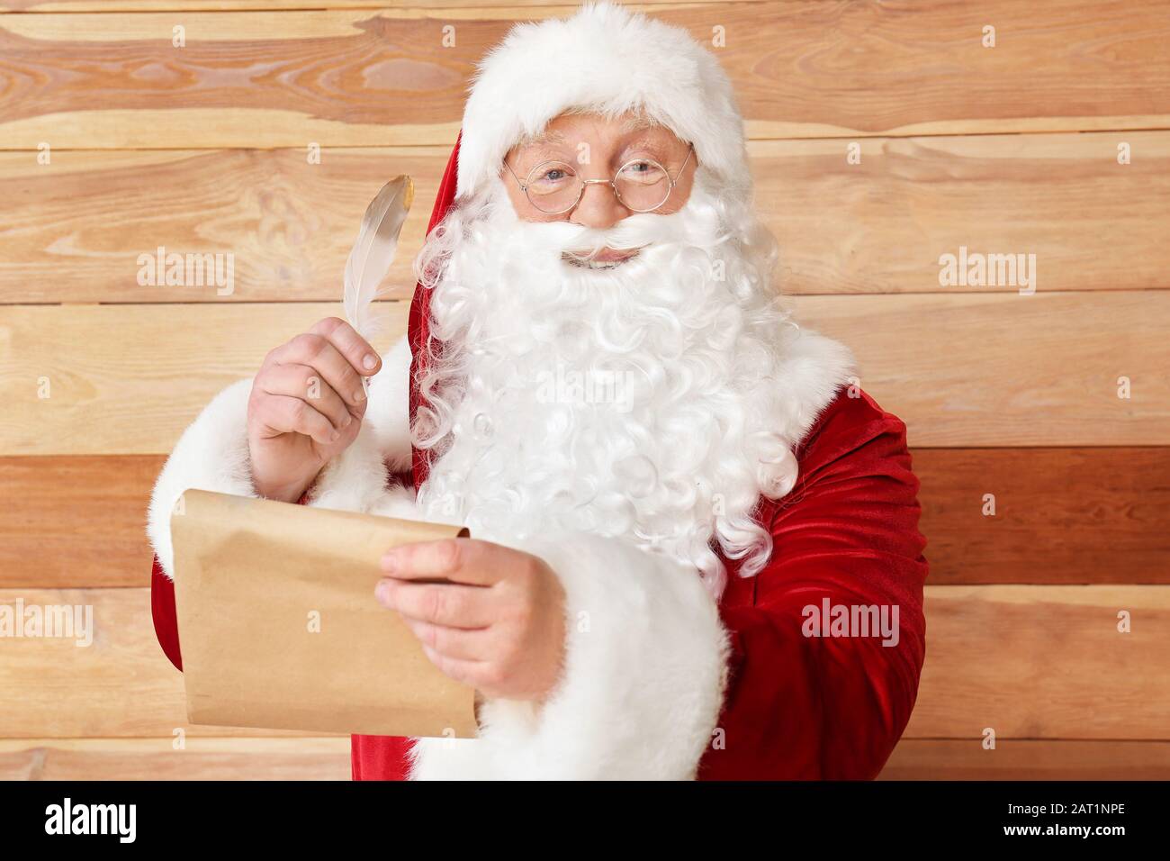 Santa Claus making list of gifts on wooden background Stock Photo - Alamy