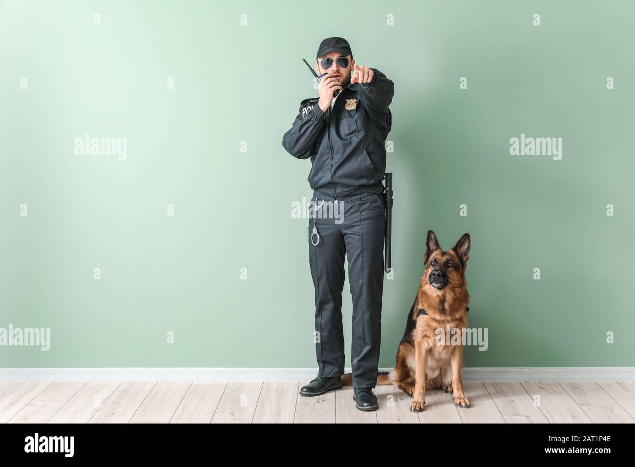 Male police officer with dog near color wall Stock Photo - Alamy