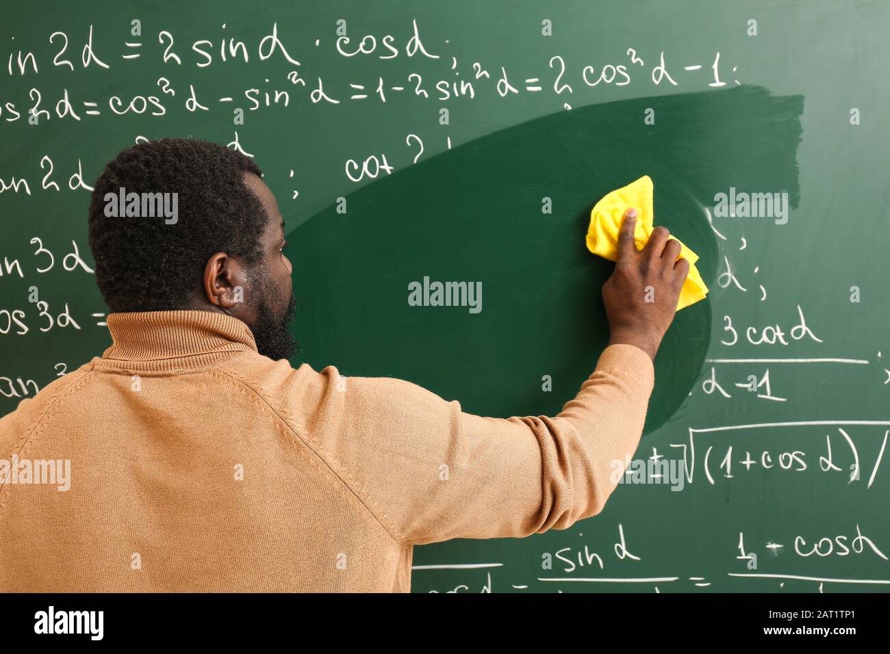 African-American math teacher wiping blackboard in classroom Stock ...