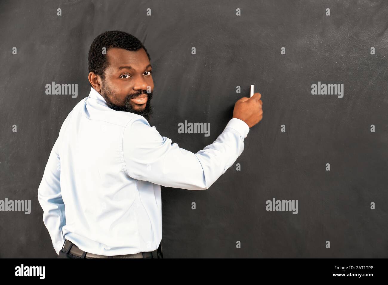 African-American teacher writing on blackboard in classroom Stock Photo ...
