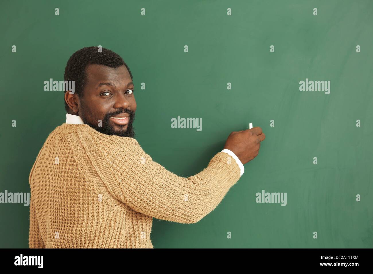 African-American teacher writing on blackboard in classroom Stock Photo ...