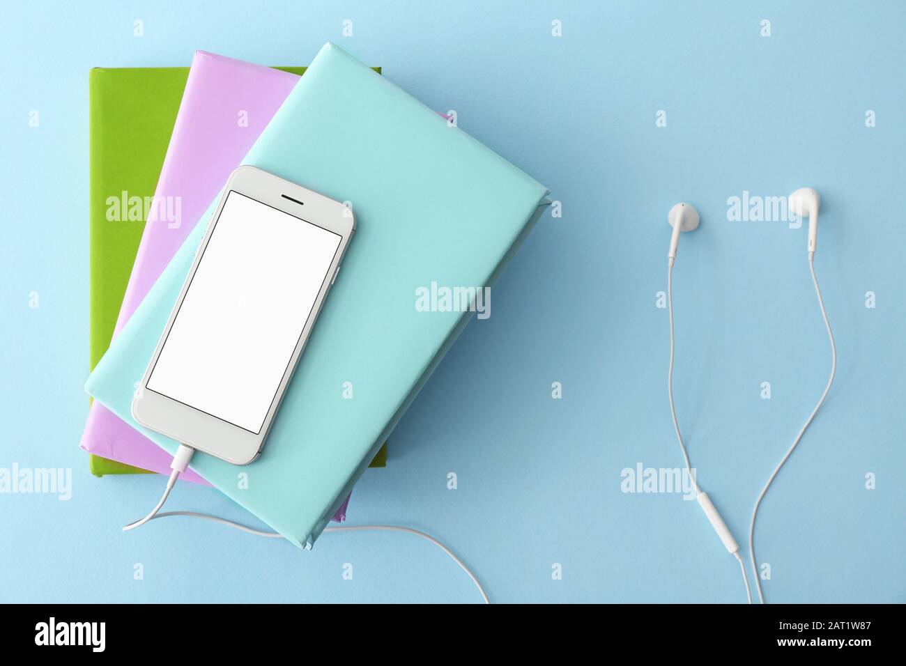 Books, mobile phone and modern earphones on color background. Concept ...