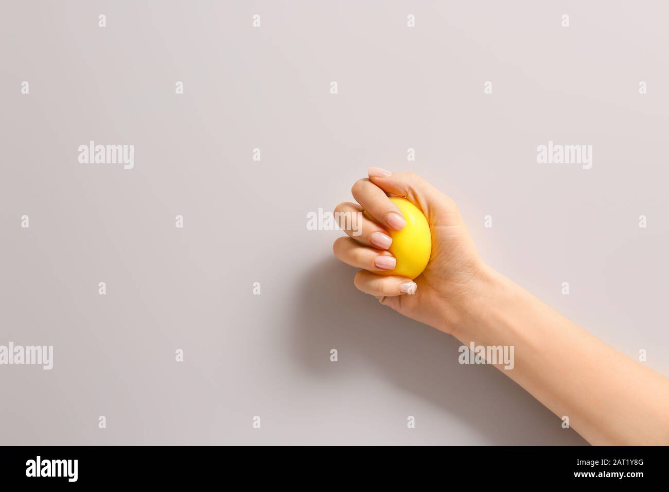 Hand squeezing stress ball on light background Stock Photo - Alamy