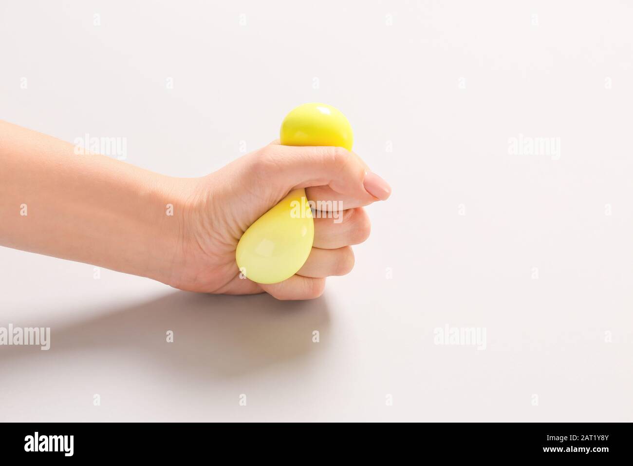 Hand squeezing stress ball on light background Stock Photo - Alamy