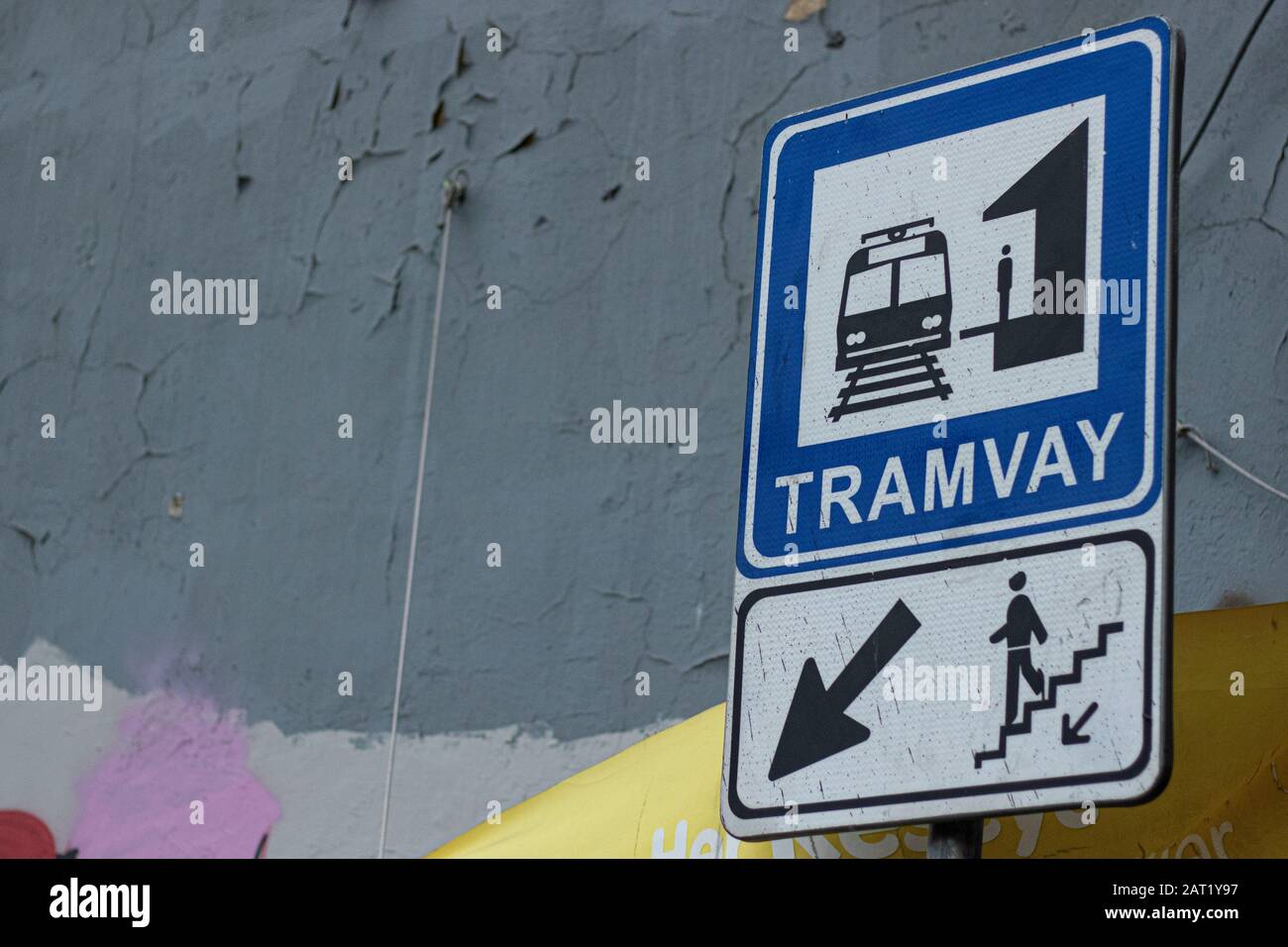Blue signage indicating the tram station. Colorful wall in the back ...