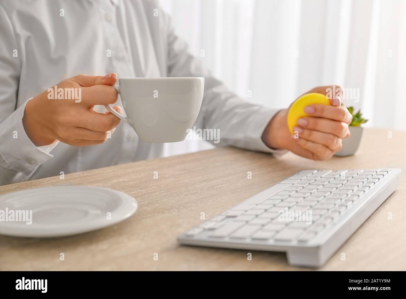 Woman squeezing stress ball while working in office Stock Photo - Alamy