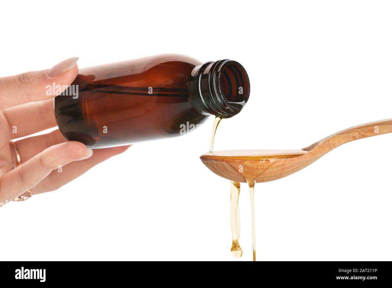 Pouring of fish oil from bottle into spoon against white background ...