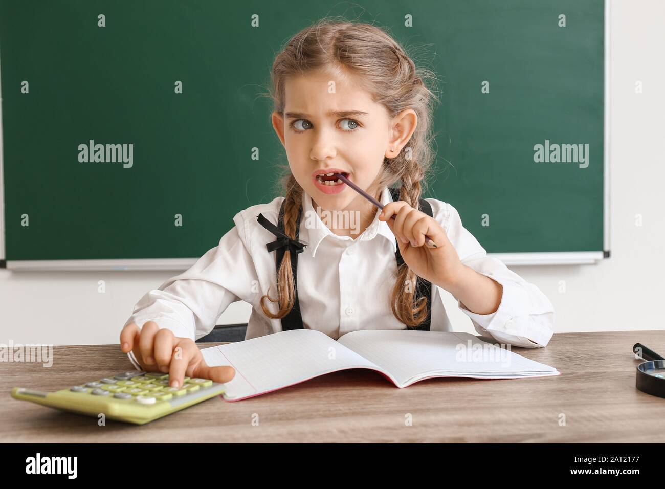 Little schoolgirl doing task in classroom Stock Photo - Alamy