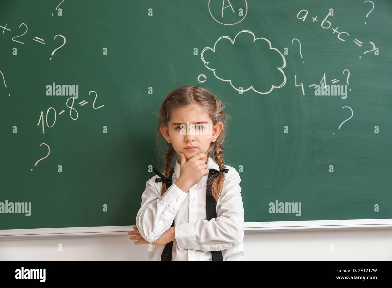 Thoughtful little schoolgirl near blackboard in classroom Stock Photo ...