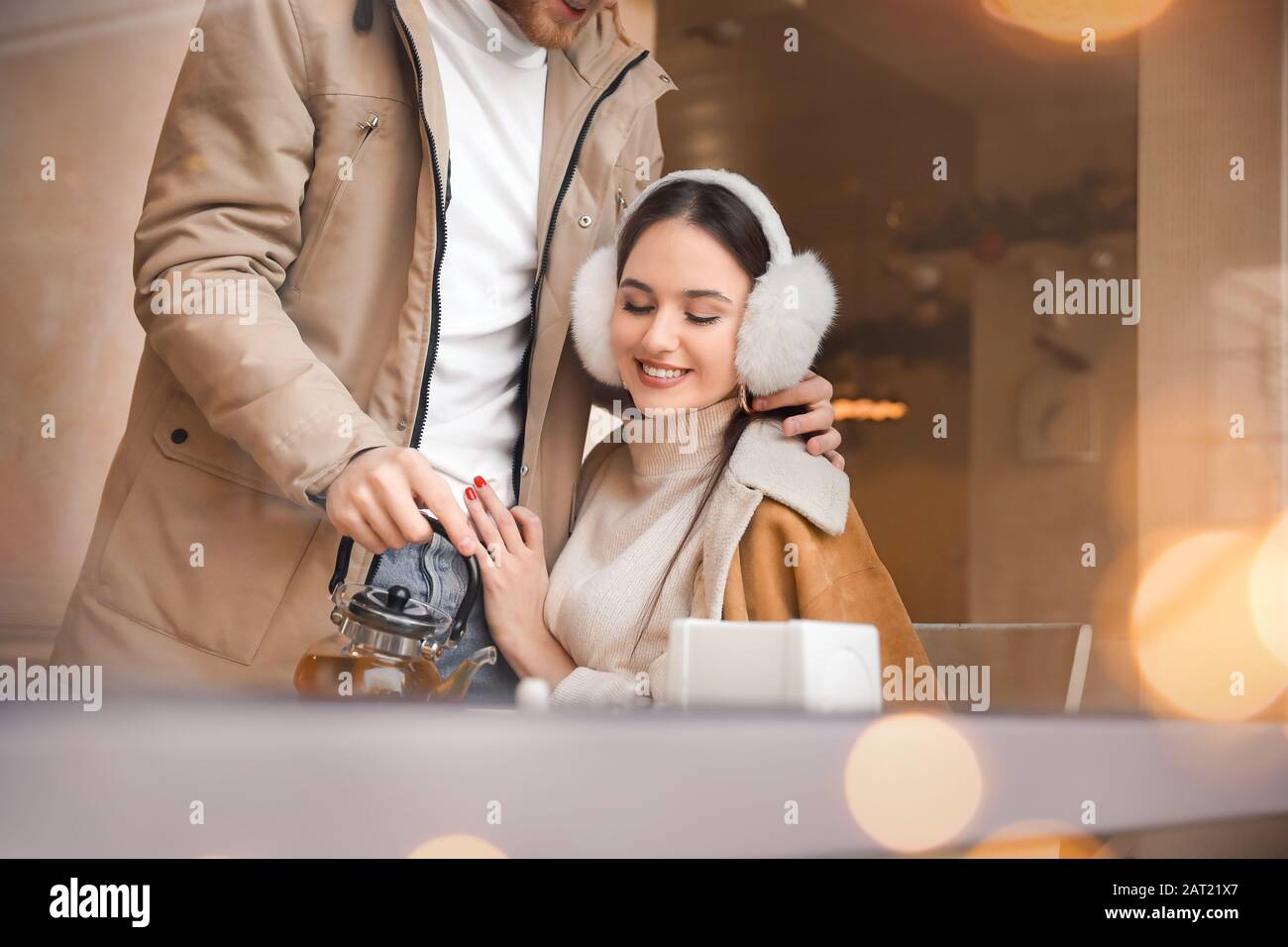 Happy young couple sitting in cafe, view through glass window Stock ...
