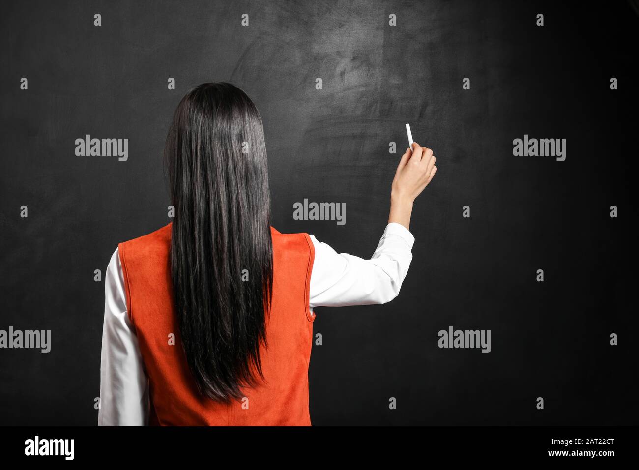 Female teacher writing on blackboard in classroom Stock Photo - Alamy