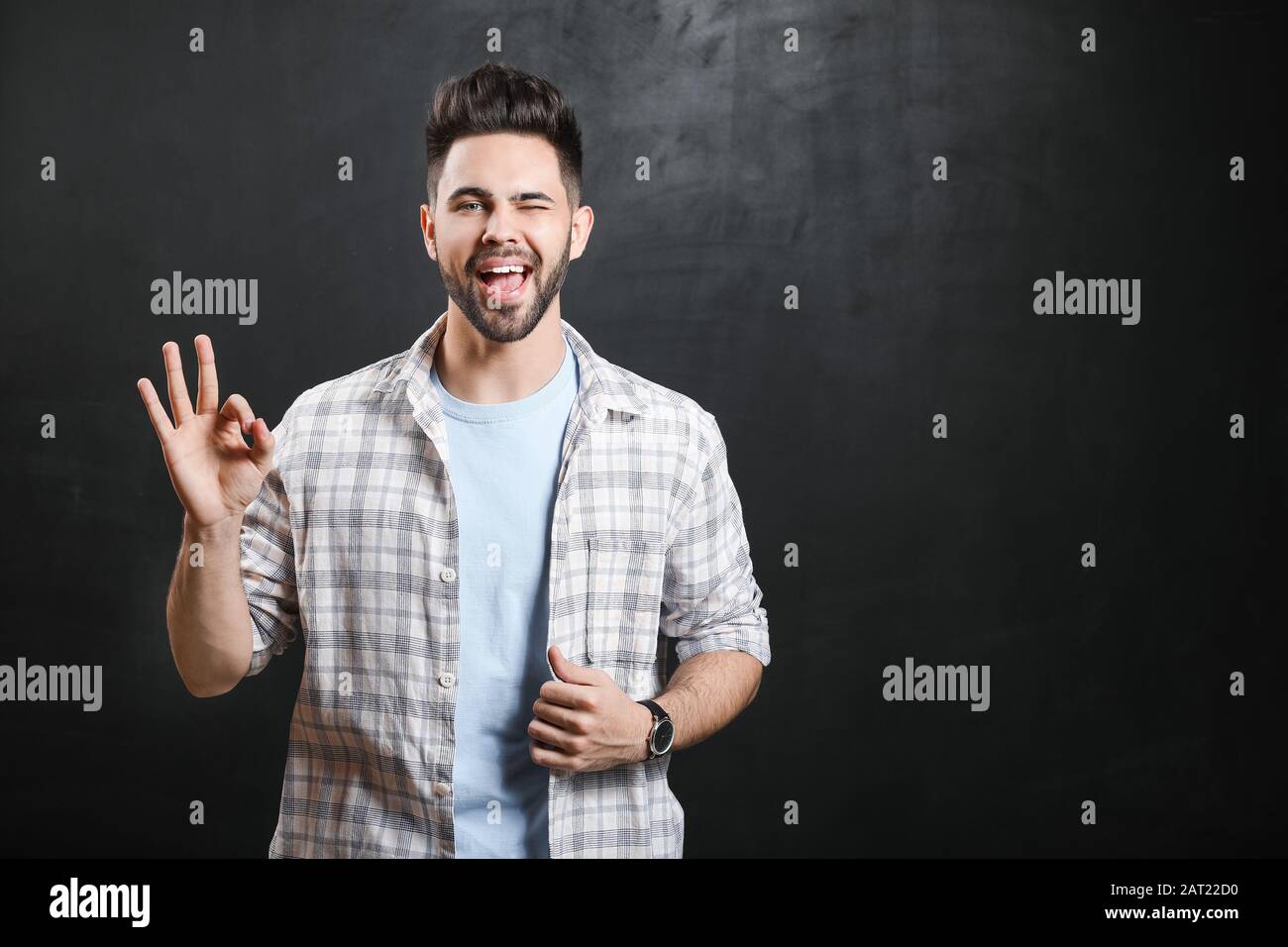 Male student showing OK near blackboard in classroom Stock Photo - Alamy