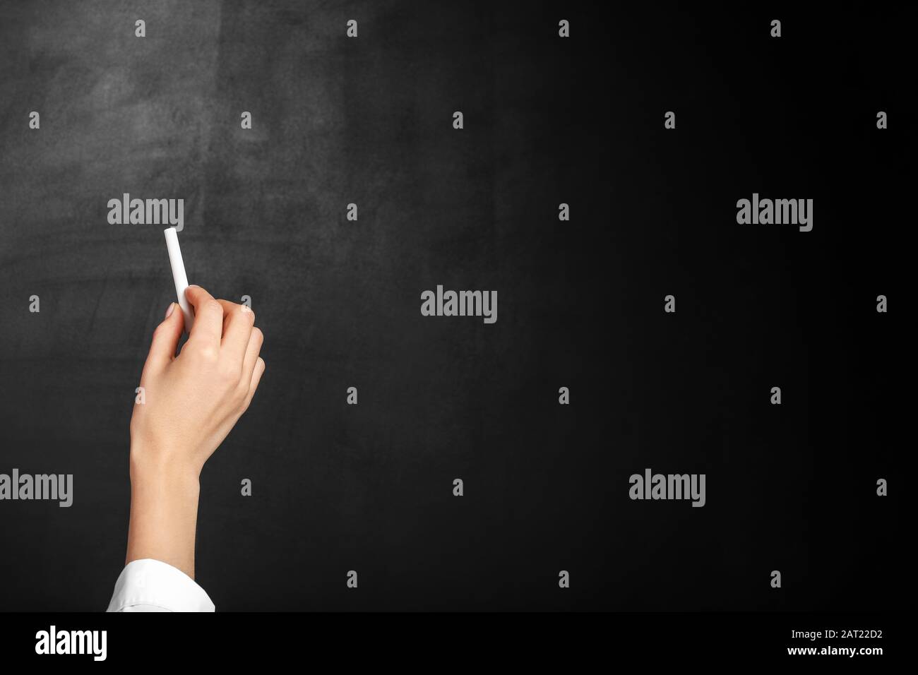 Female teacher writing on blackboard in classroom Stock Photo - Alamy