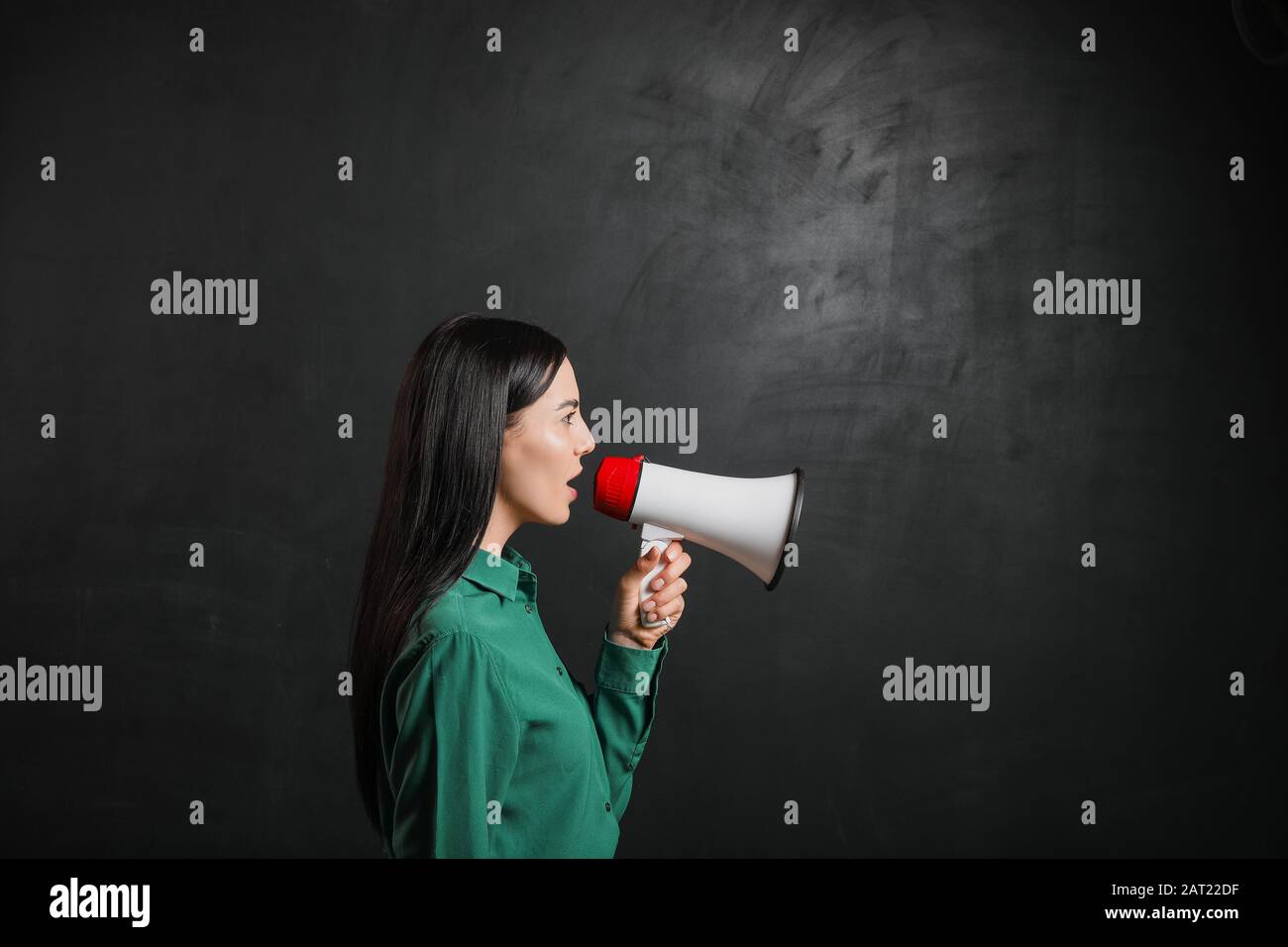 Female teacher with megaphone near blackboard in classroom Stock Photo ...