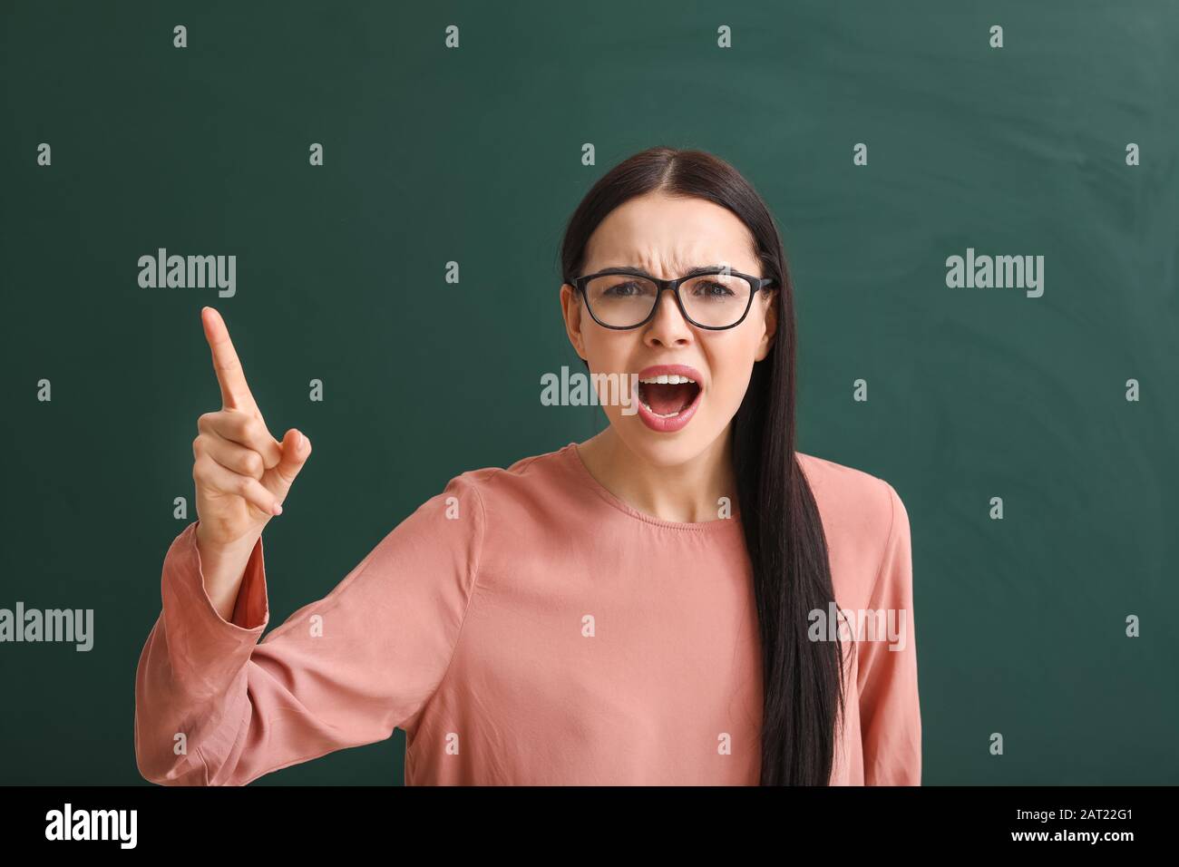 Angry female teacher near blackboard in classroom Stock Photo - Alamy