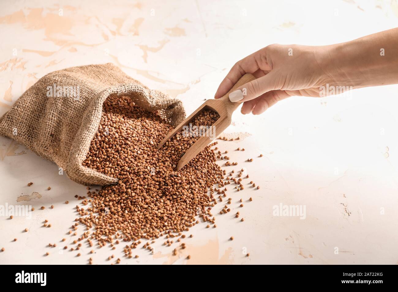 Female hand with scoop and bag with raw buckwheat on table Stock Photo ...