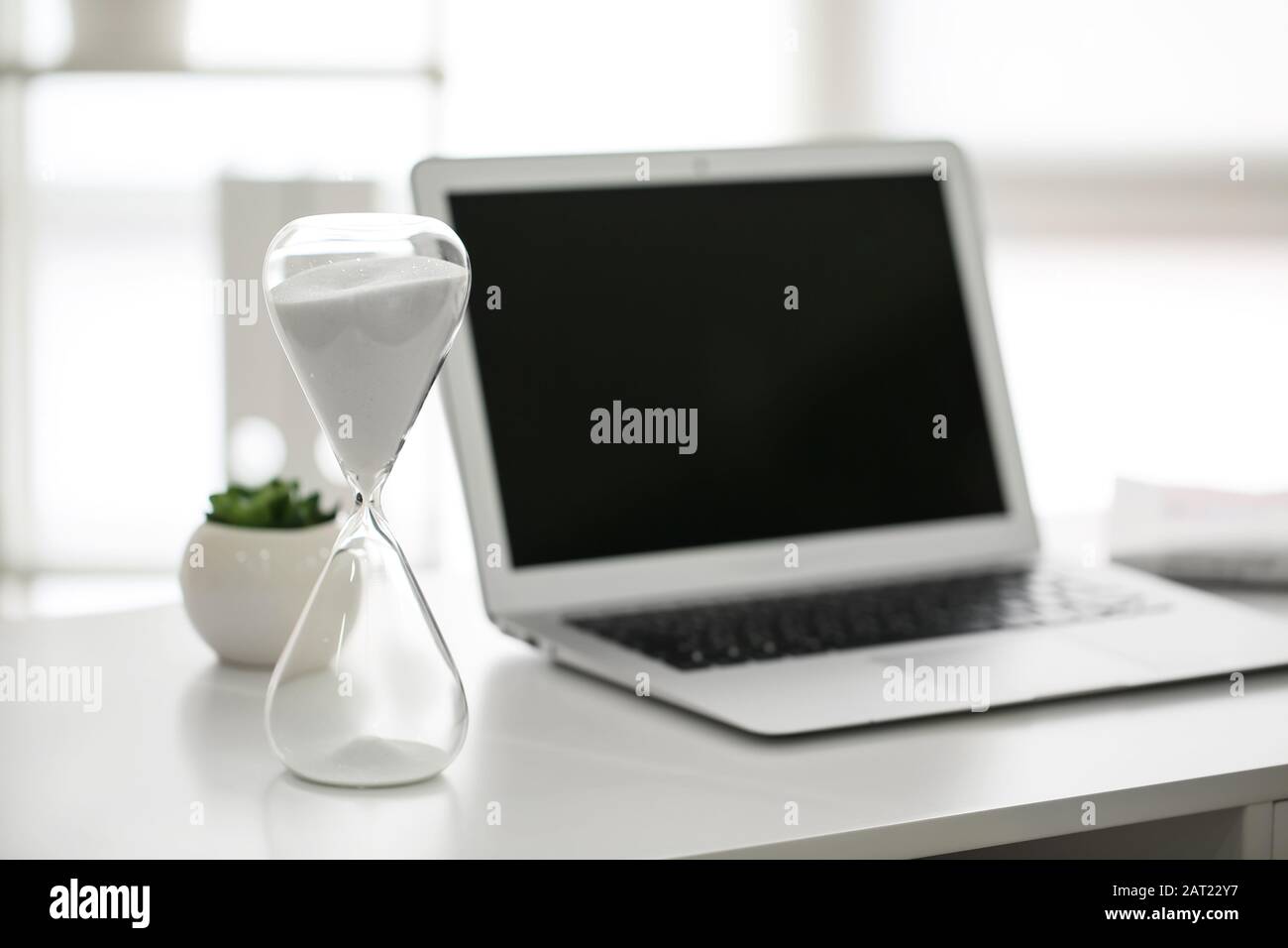Hourglass with laptop on table in office. Time management concept Stock ...