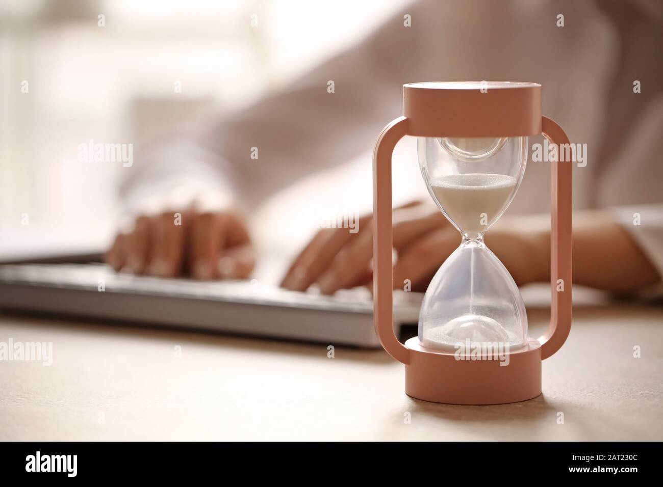 Hourglass and woman working on computer at table in office Stock Photo ...